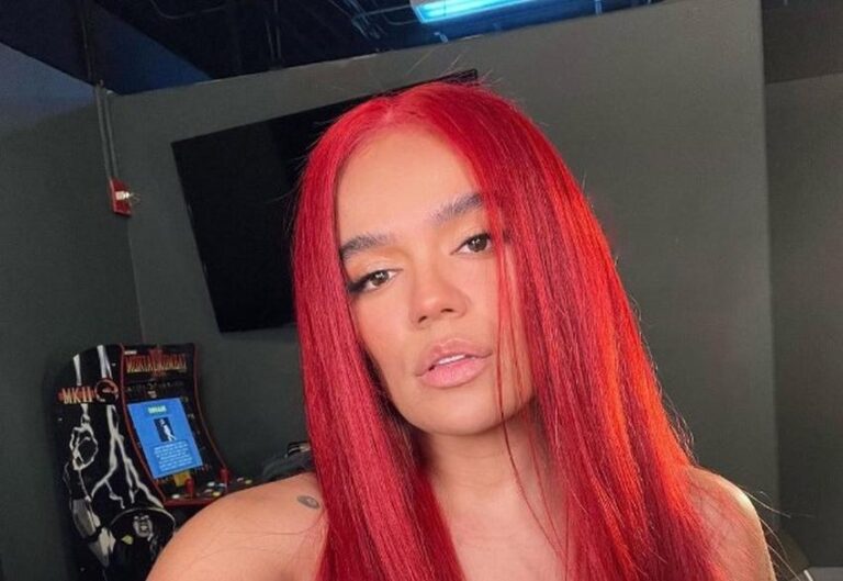 Karol G solo con su larga cabellera roja y unas medias de malla negra ...